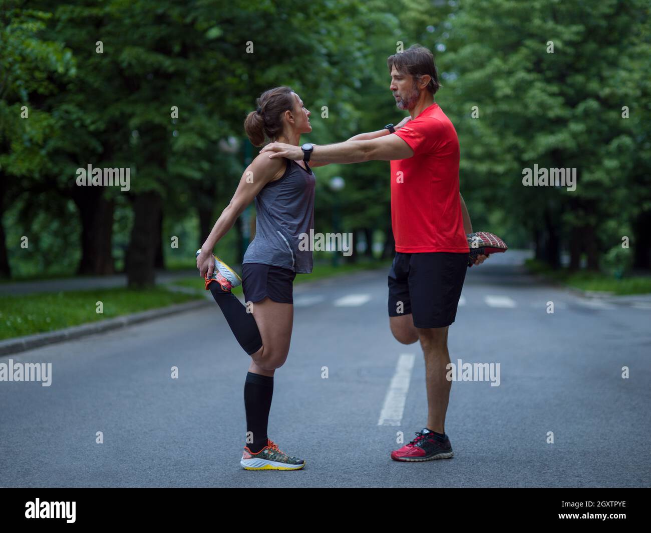 healthy runners team warming up and stretching in city park before ...