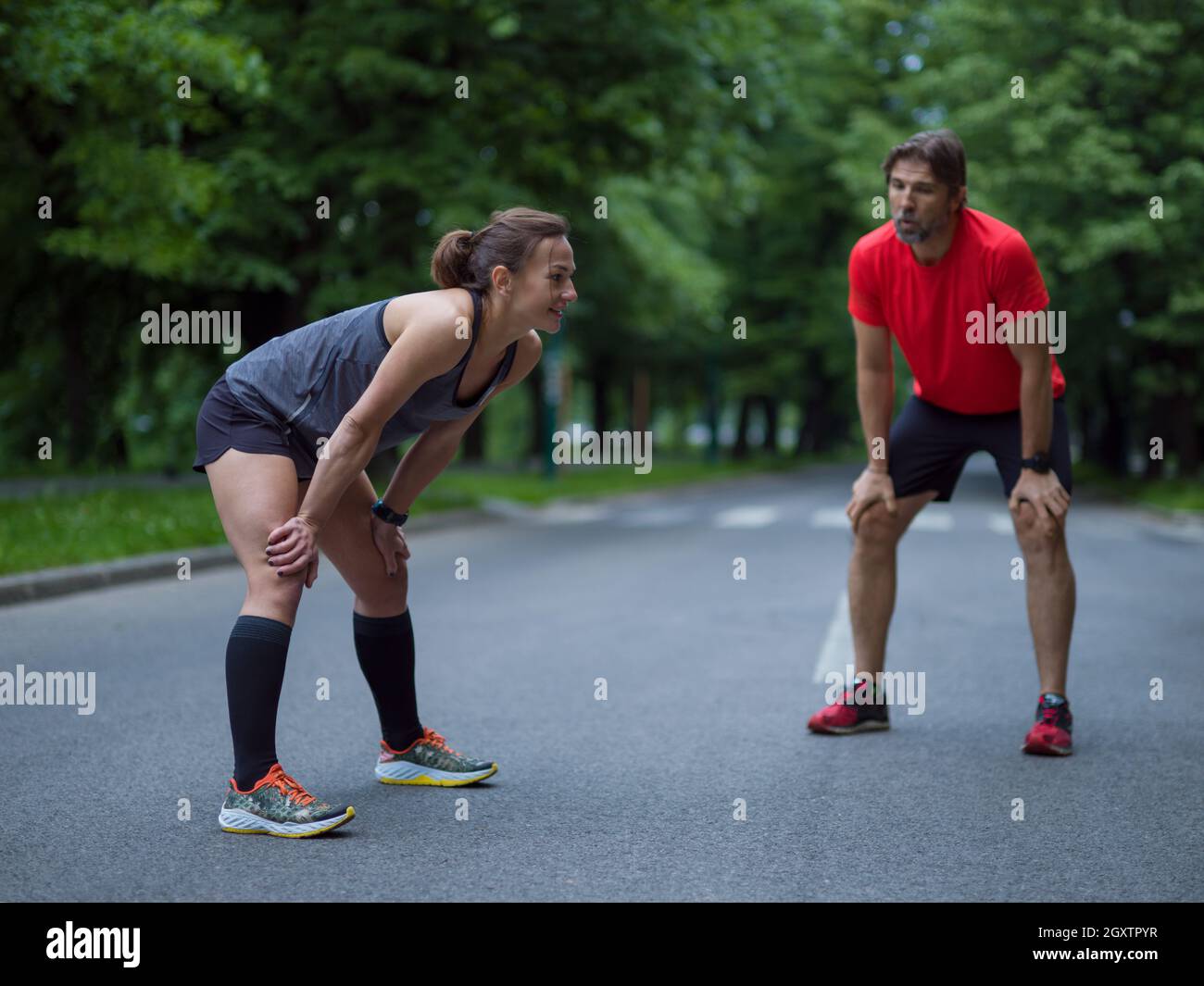 healthy runners team warming up and stretching in city park before ...