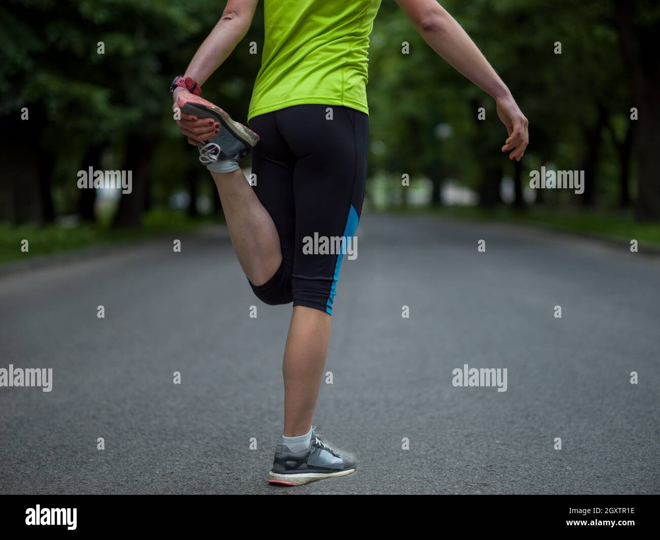 healthy female runner warming up and stretching in city park before ...