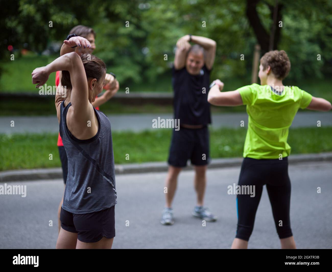 healthy runners team warming up and stretching in city park before ...