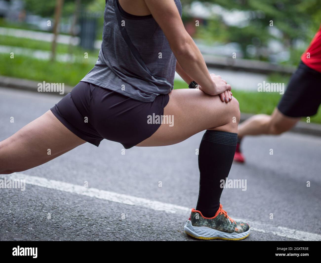 healthy runners team warming up and stretching in city park before ...