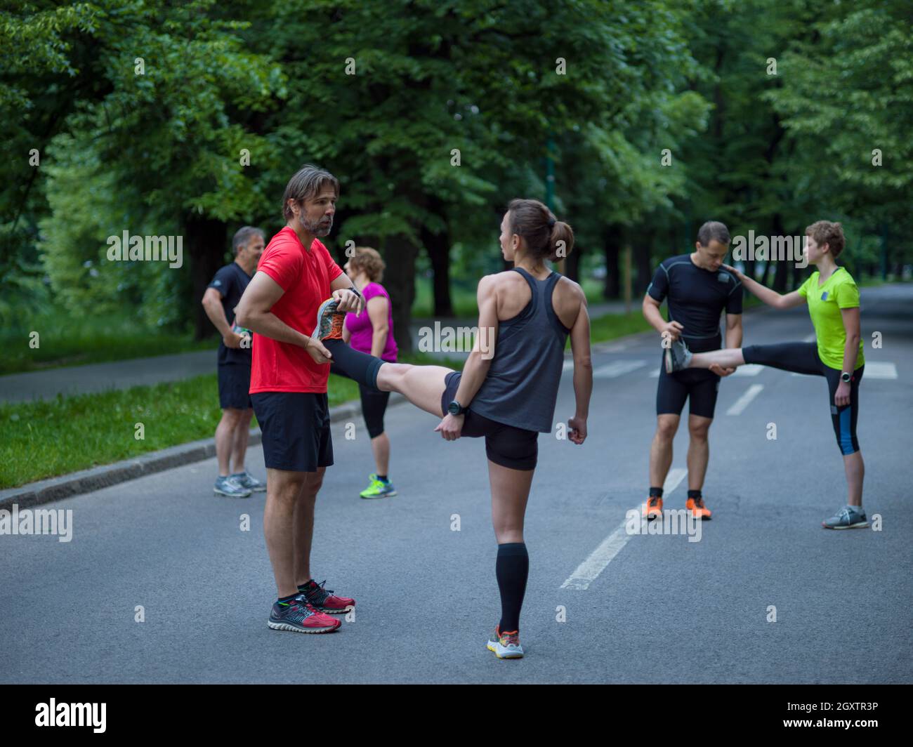 healthy runners team warming up and stretching in city park before ...