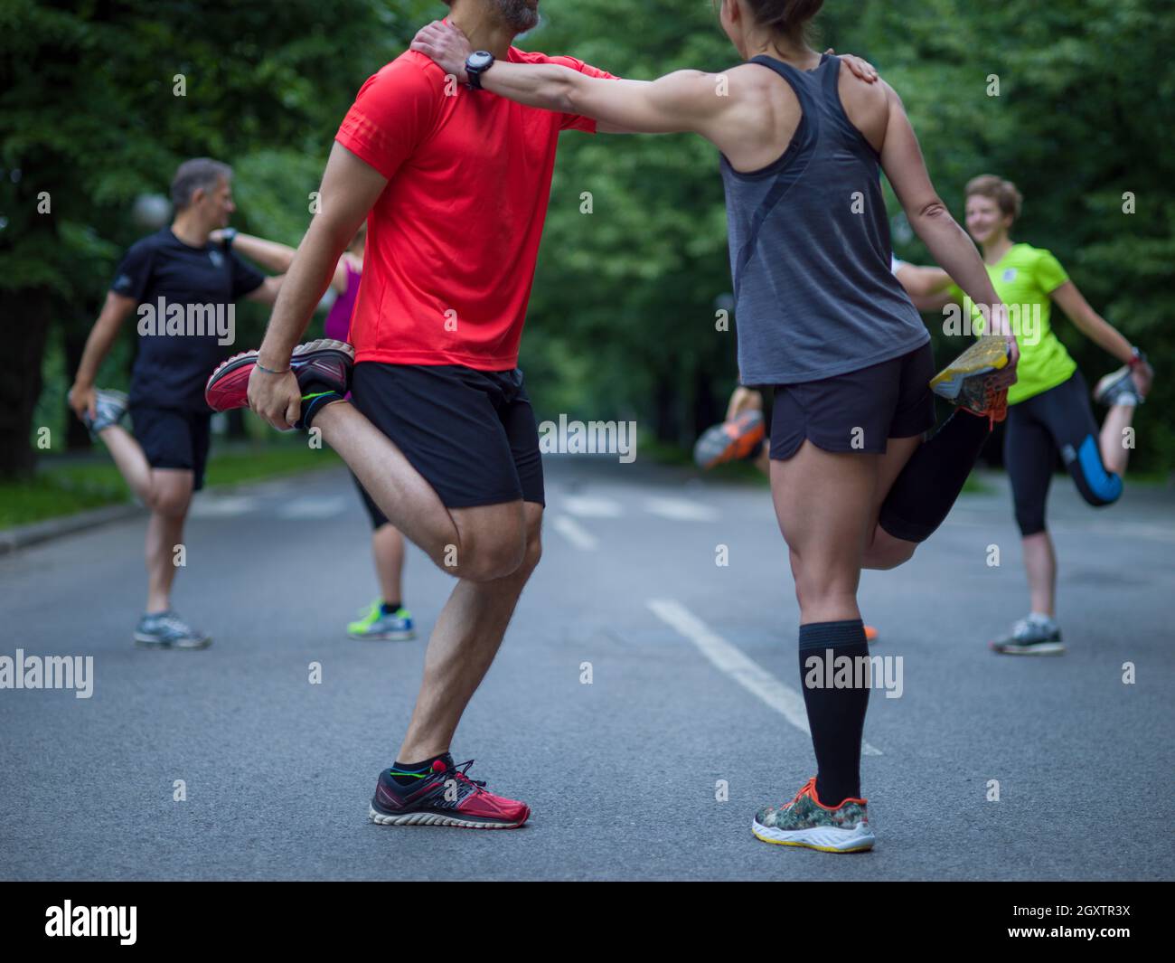 healthy runners team warming up and stretching in city park before ...