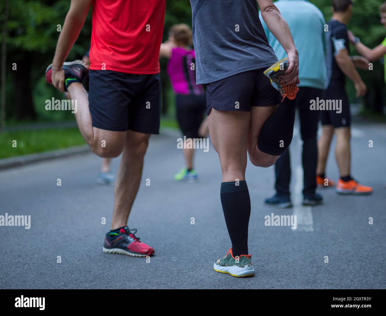 healthy runners team warming up and stretching in city park before ...