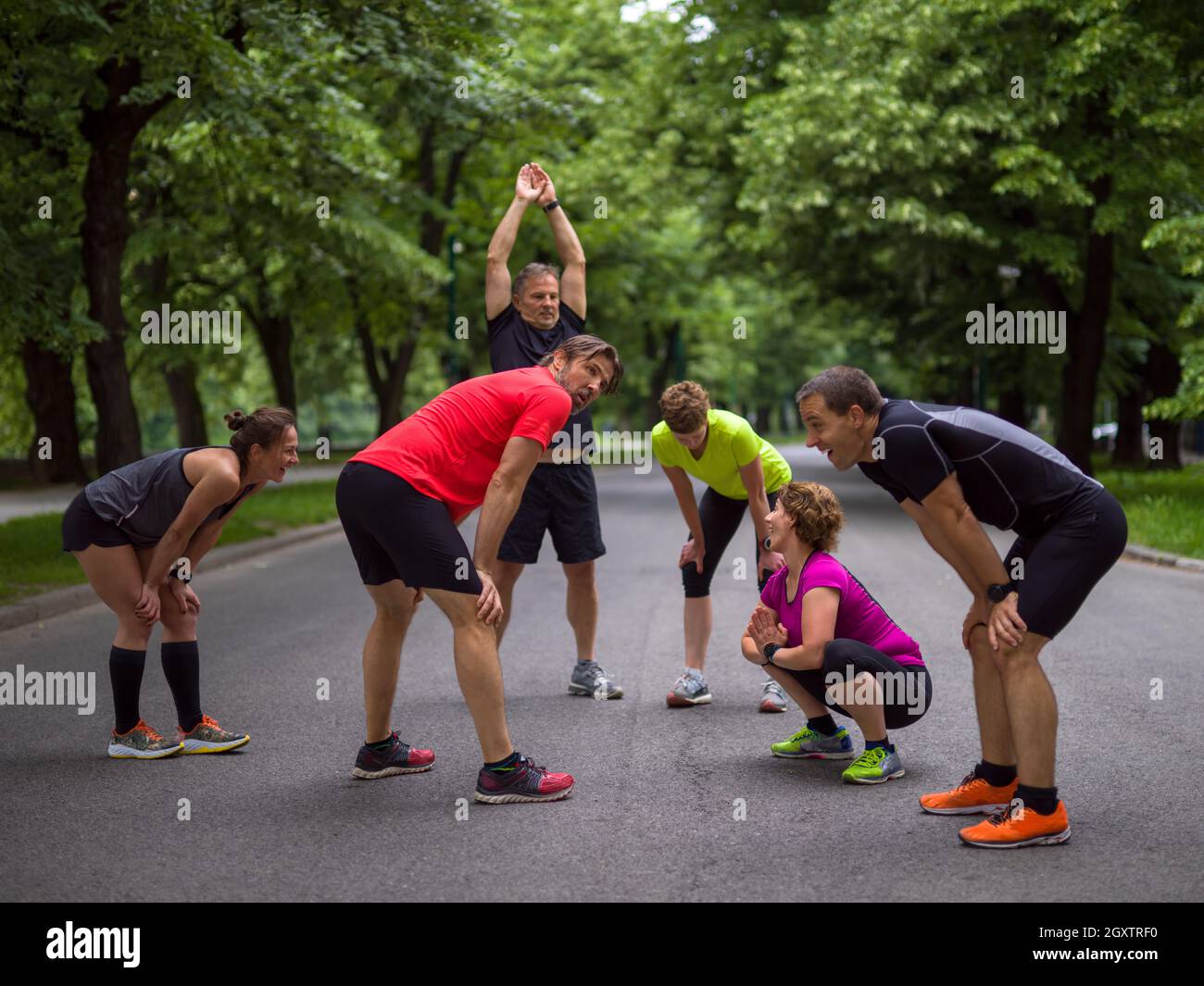 healthy runners team warming up and stretching in city park before ...