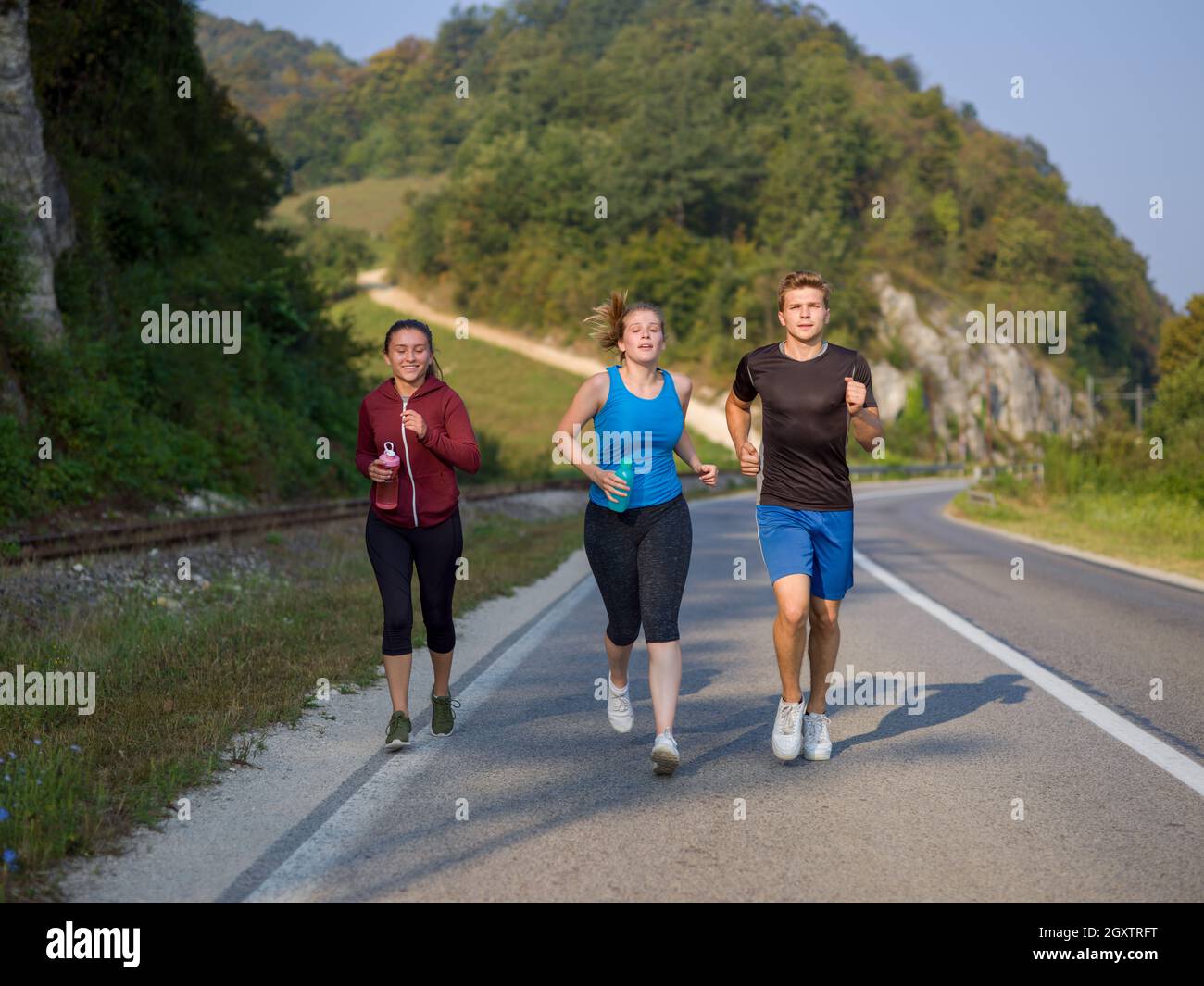 group of young people jogging on country road runners running on open ...