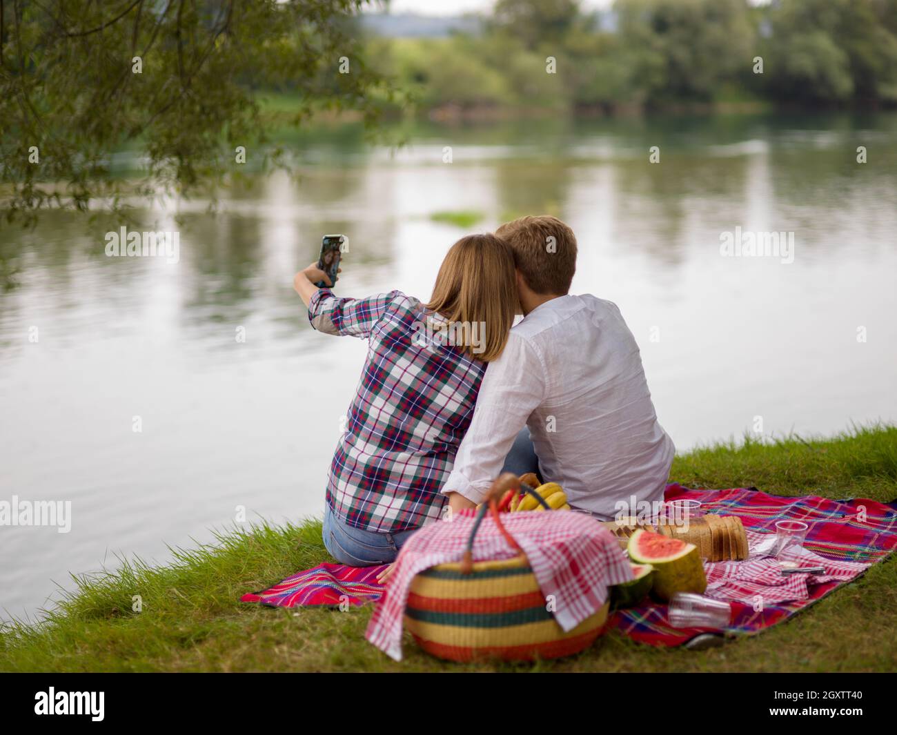 Couple in love taking a selfie by mobile phone while enjoying picnic ...