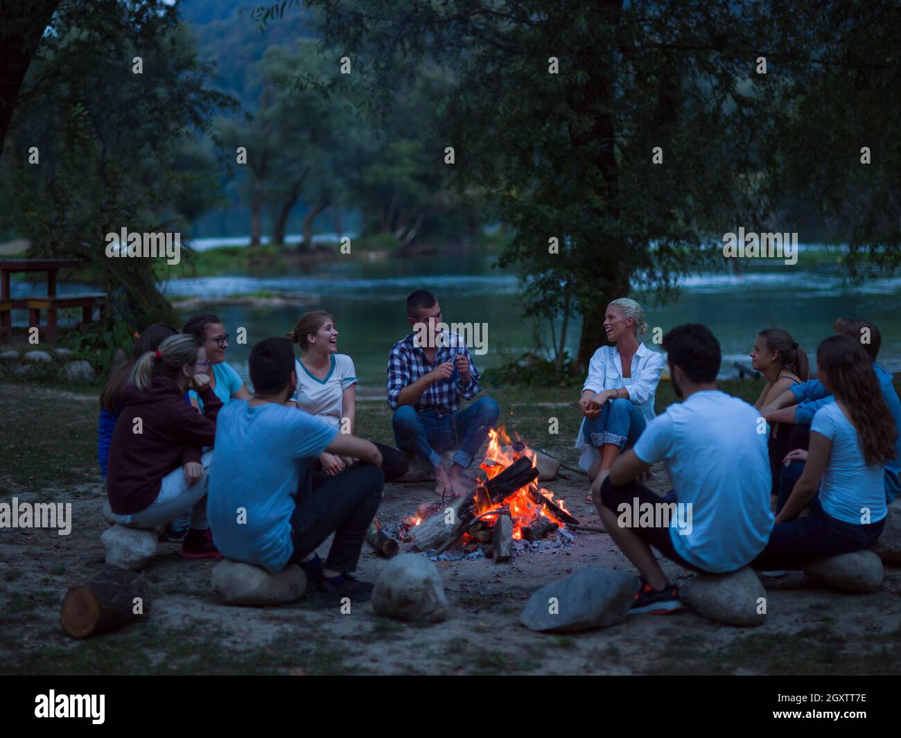 a group of happy young friends relaxing and enjoying summer evening ...