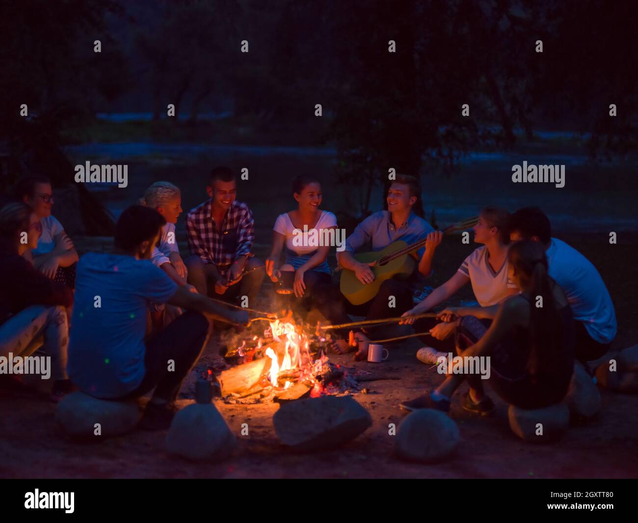 a group of happy young friends relaxing and enjoying summer evening ...