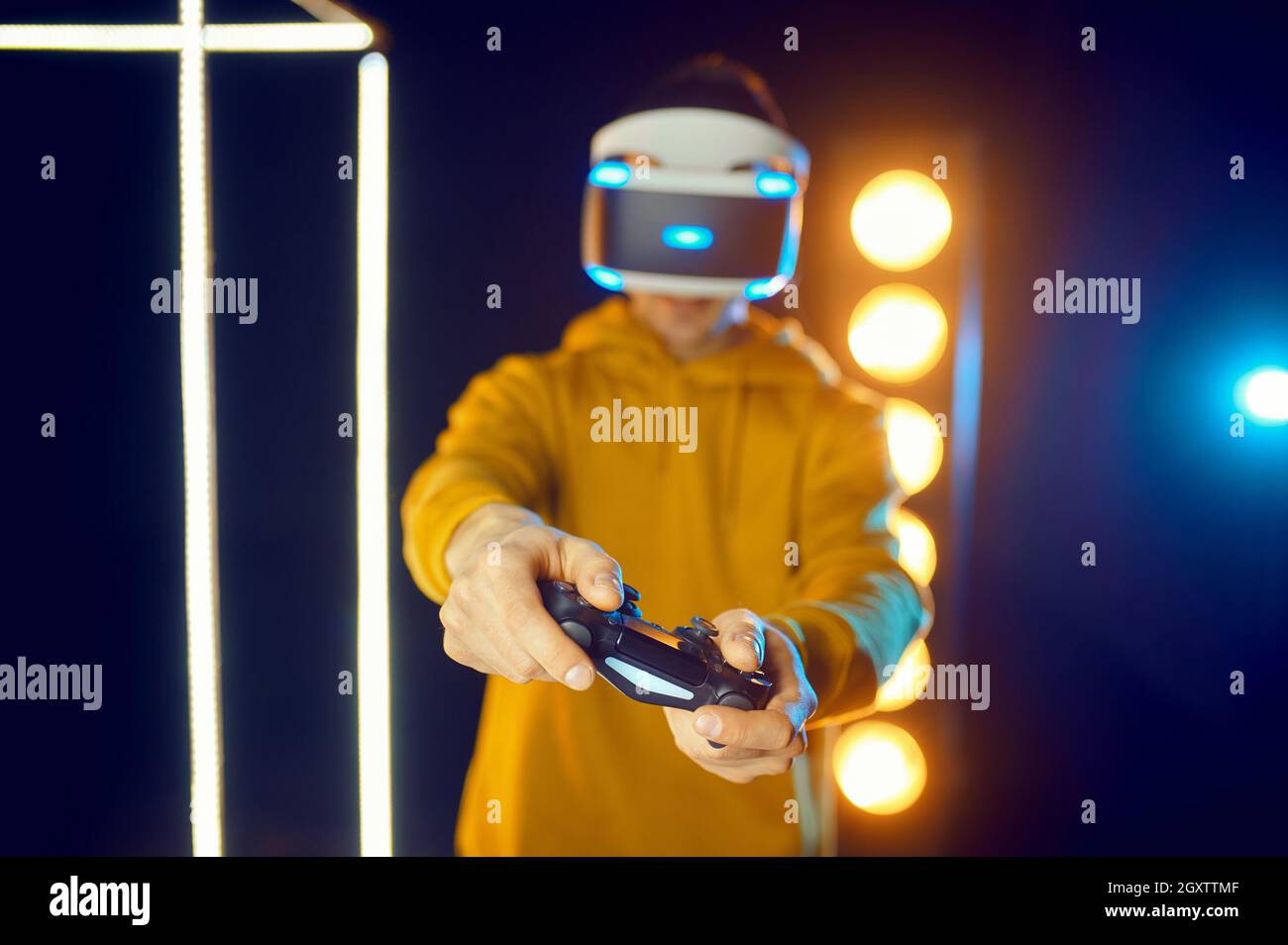 Man plays the game using virtual reality helmet and gamepad in luminous ...