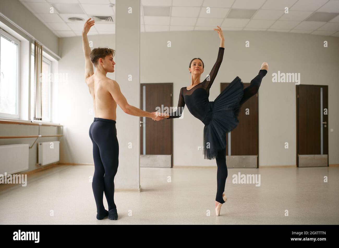 Female and male ballet dancers dancing at barre. Ballerina with partner ...