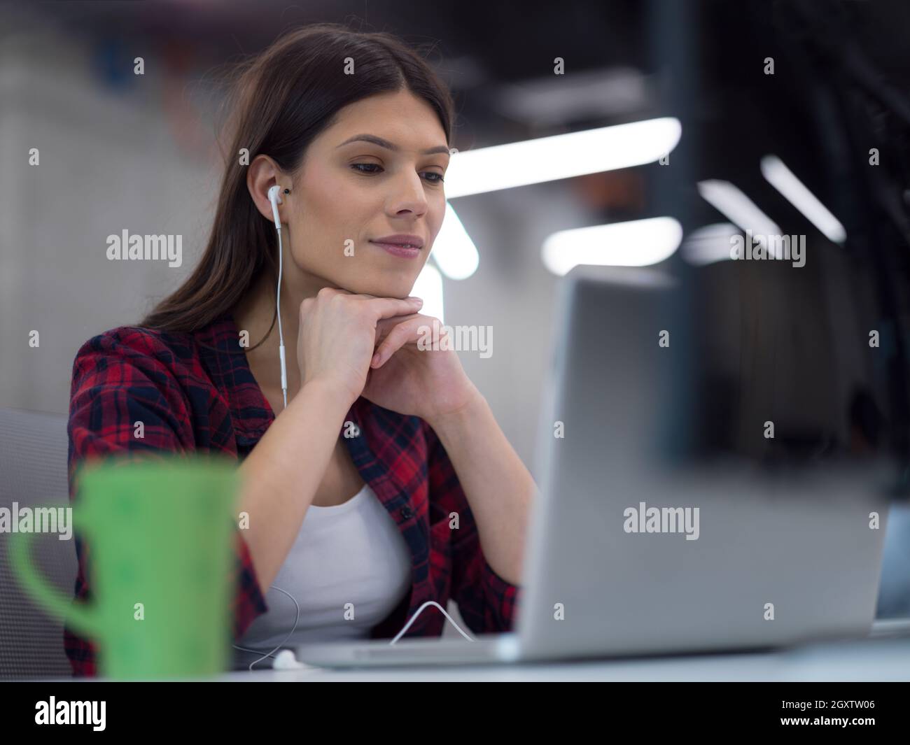 young female software developer using laptop computer while writing programming code at modern ...
