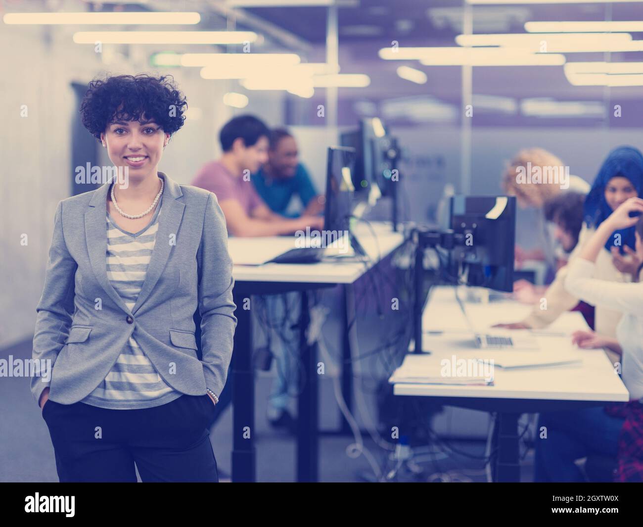 portrait of young female software developer at busy startup office with ...