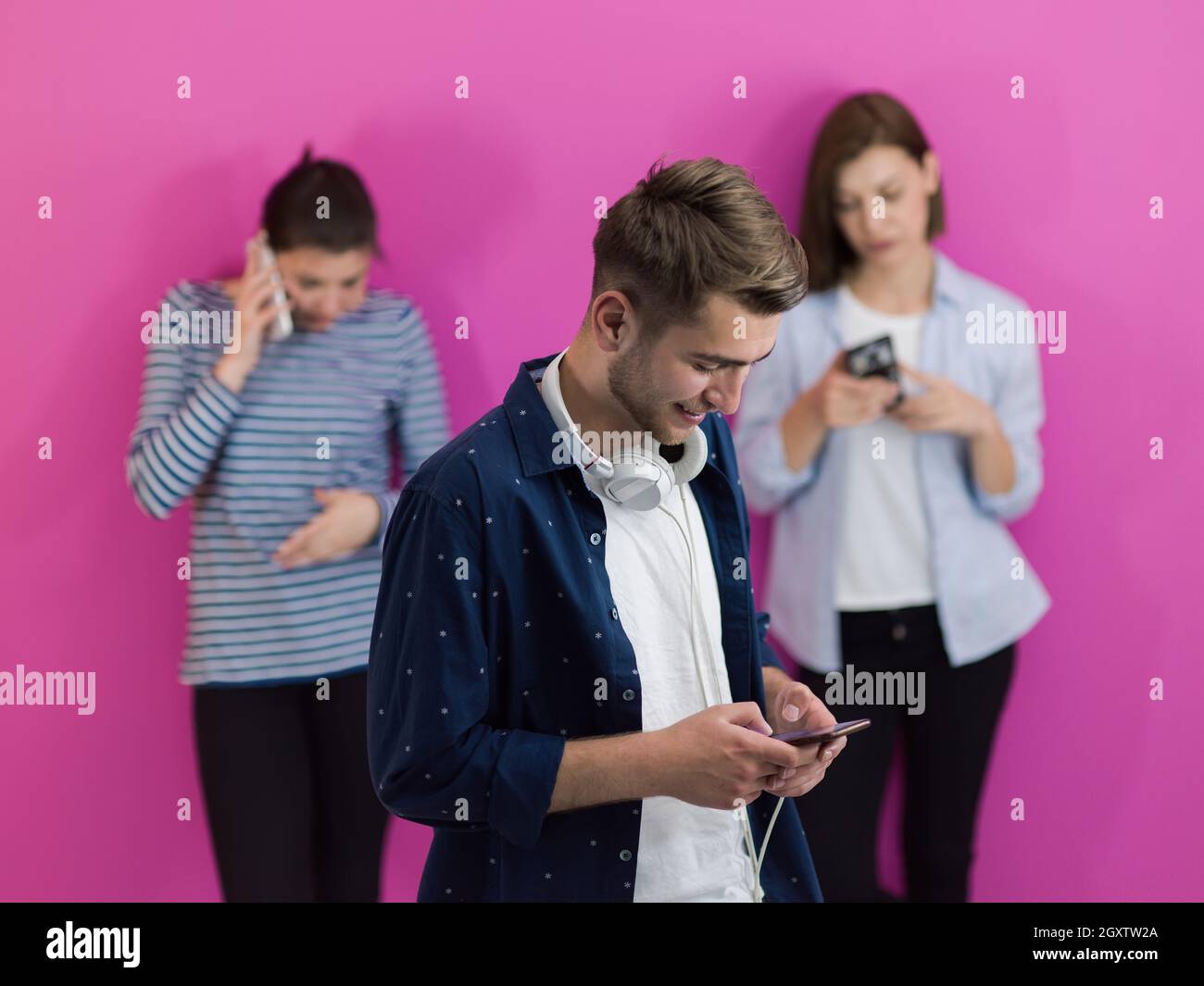a group of diverse teenagers use mobile devices while posing for studio ...