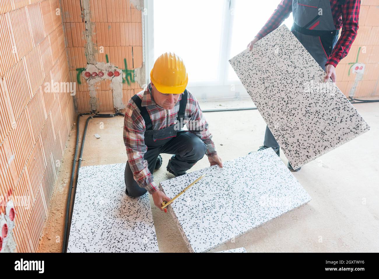 Craftsman measuring tile with ruler with his assistant at construction ...