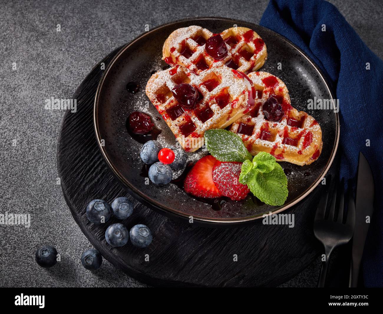 Delicious waffles heart shape with powdered sugar and berries on ...