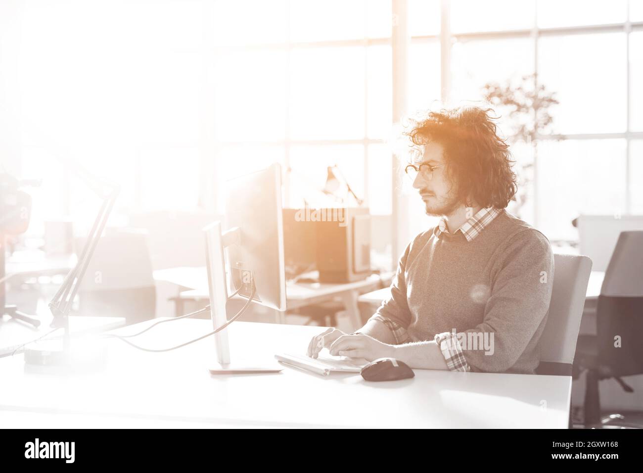 Young businessman programer in big bright office at work using computer ...