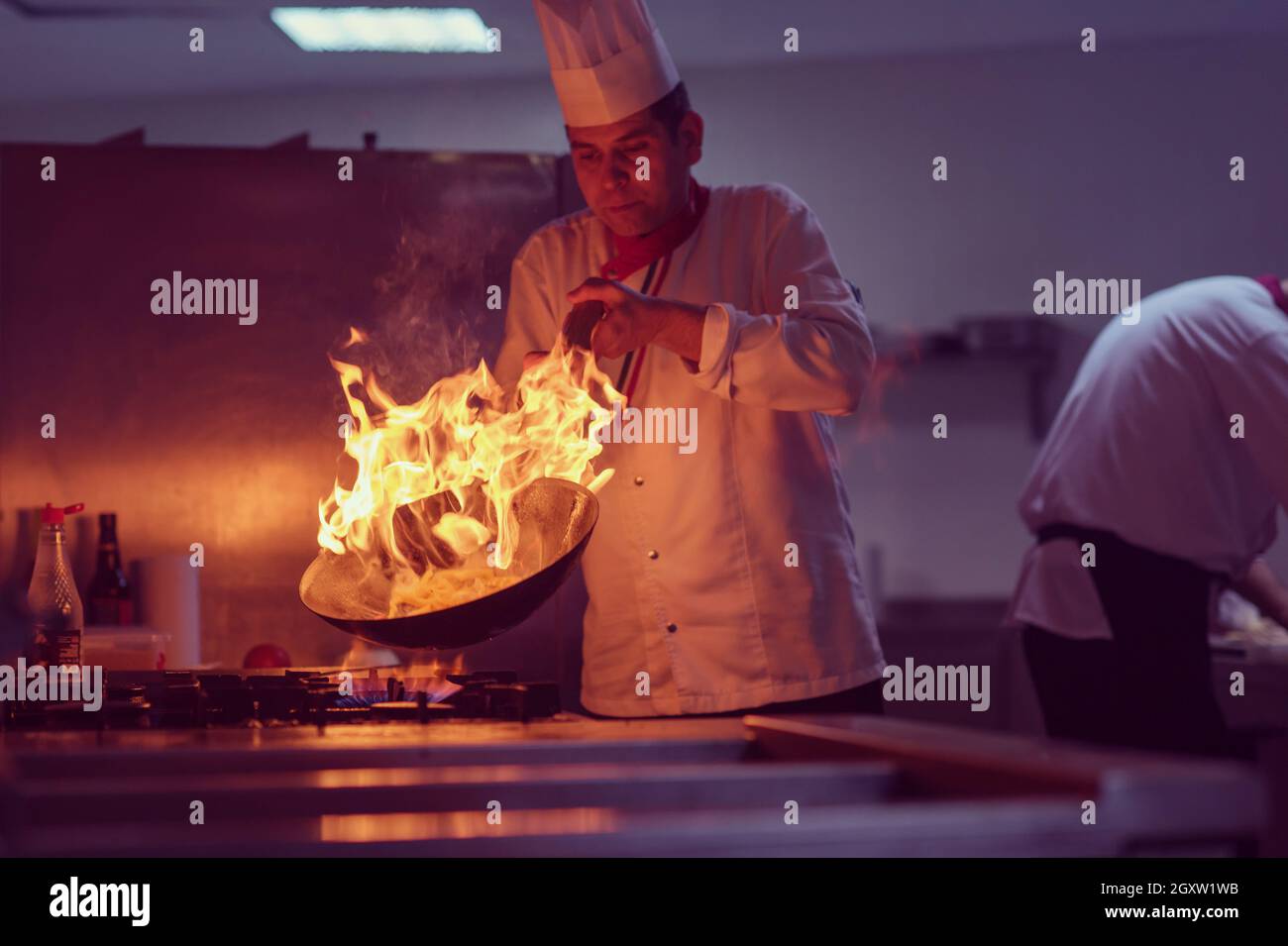 Chef cooking and doing flambe on food in restaurant kitchen Stock Photo ...