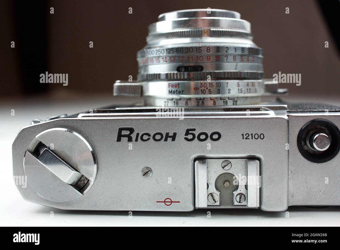 Ricoh 500 silver camera with lens pointed up against a white and gray ...