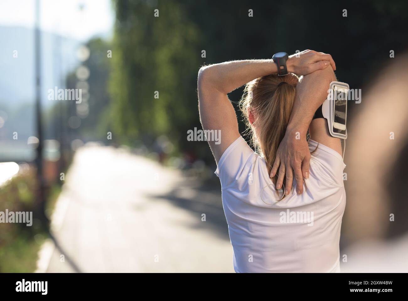 Fit blonde runner woman warming up and stretching before morning ...