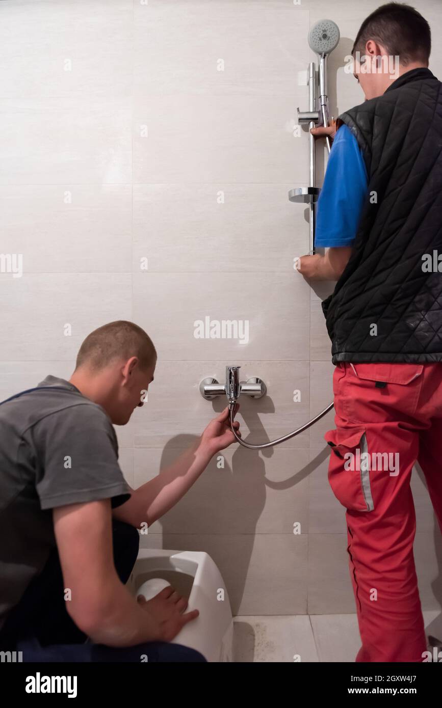 two professional plumbers working together in a bathroom, plumbing ...