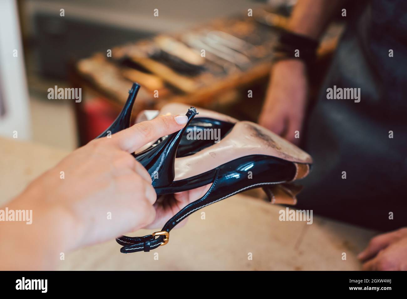 Customer bringing shoes to the shoemaker for a repair of the heels ...