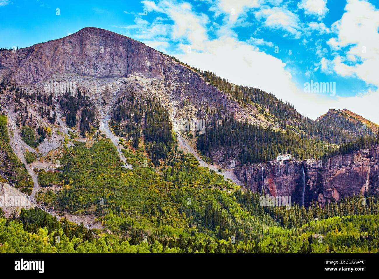 View of large mountain of grey rock, aspen trees, and pine trees Stock ...