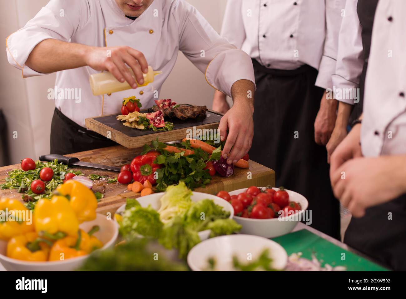 Professional team cooks and chefs preparing meal at busy hotel or ...