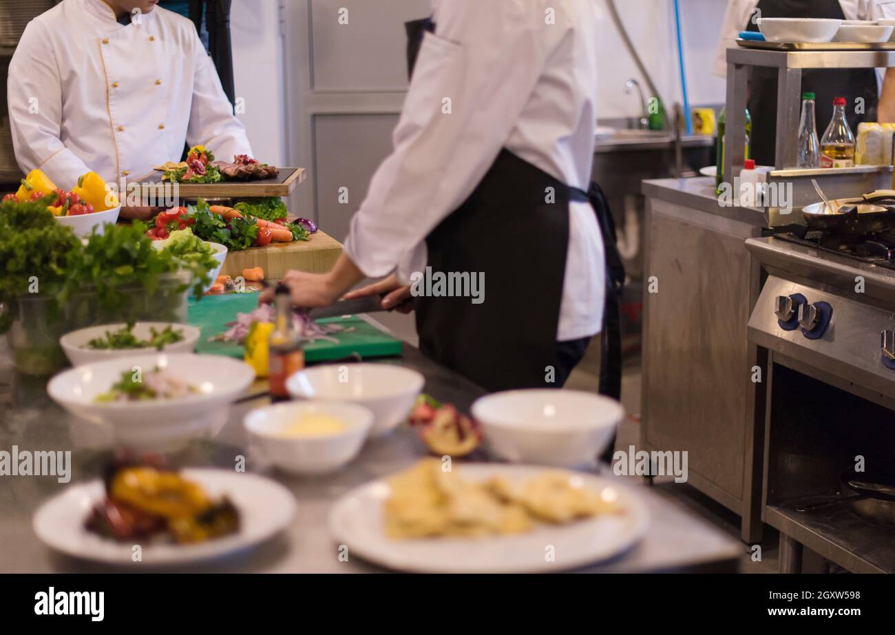 Professional team cooks and chefs preparing meal at busy hotel or ...