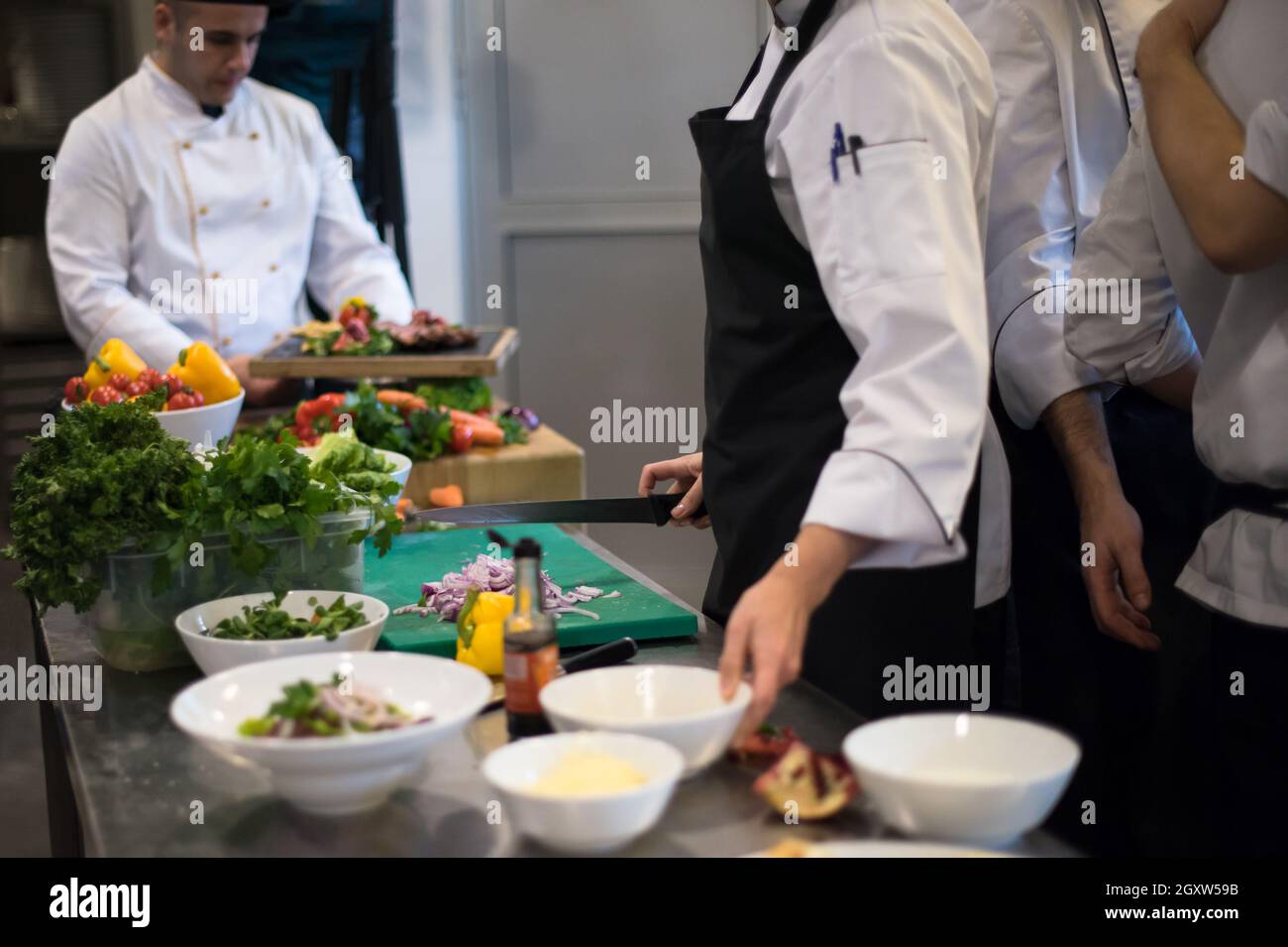 Professional team cooks and chefs preparing meal at busy hotel or ...