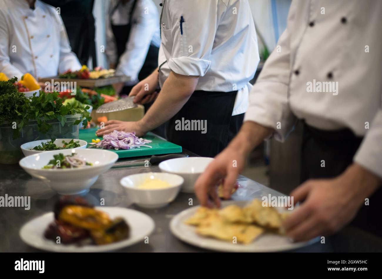 Professional team cooks and chefs preparing meal at busy hotel or ...