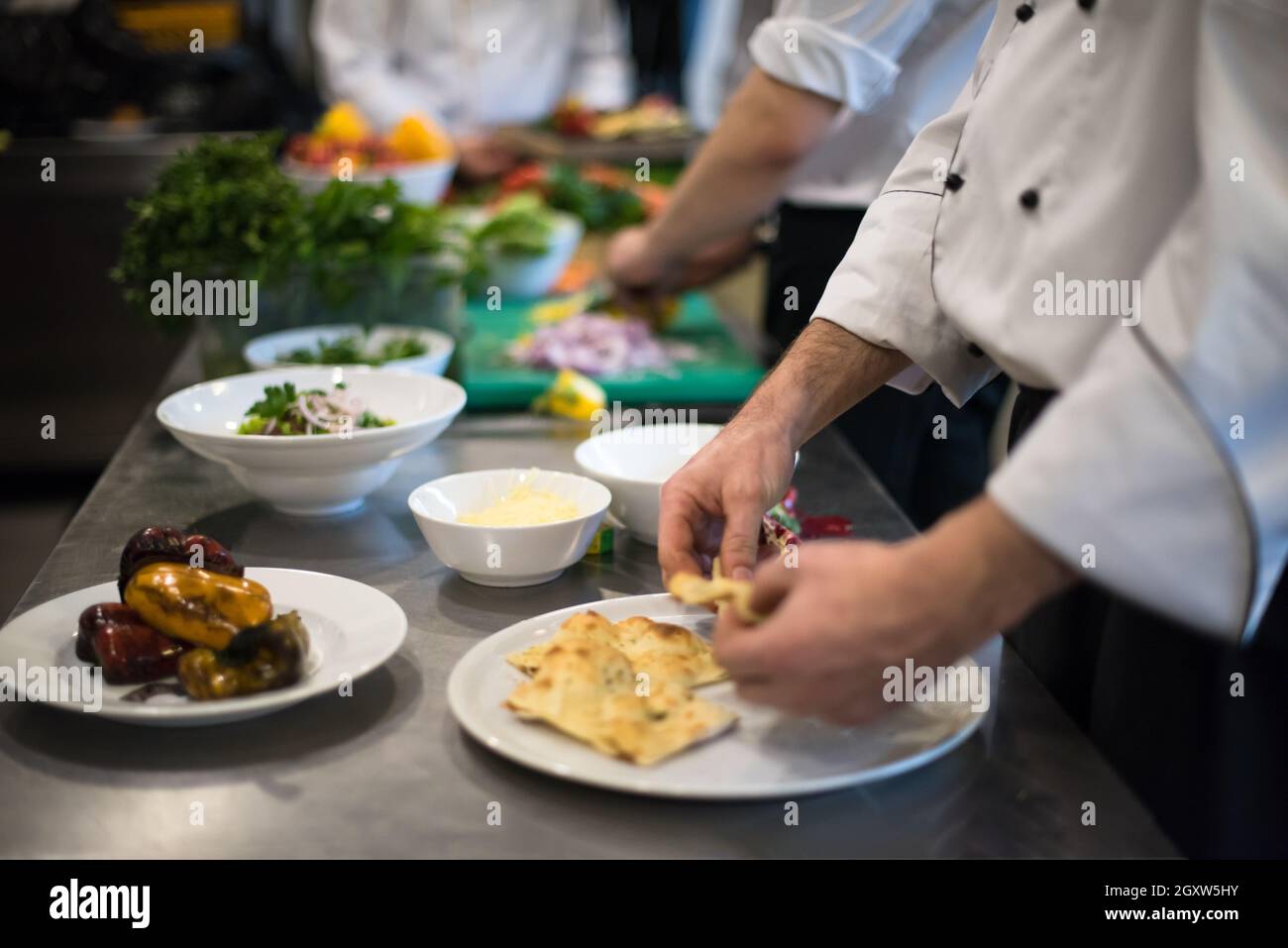 Professional team cooks and chefs preparing meal at busy hotel or ...