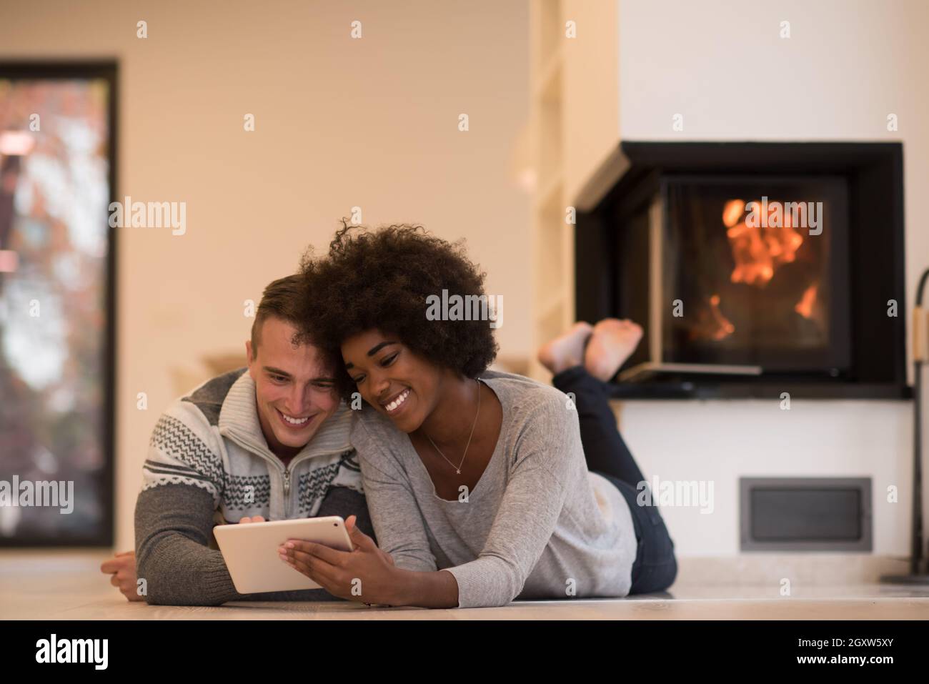beautiful young multiethnic couple using tablet computer on the floor ...