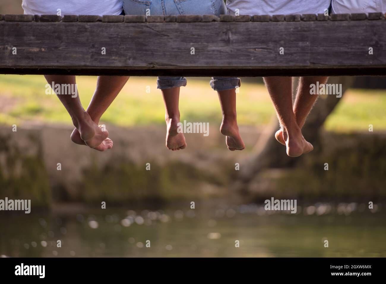 group of people sitting at wooden bridge over the river with a focus on ...