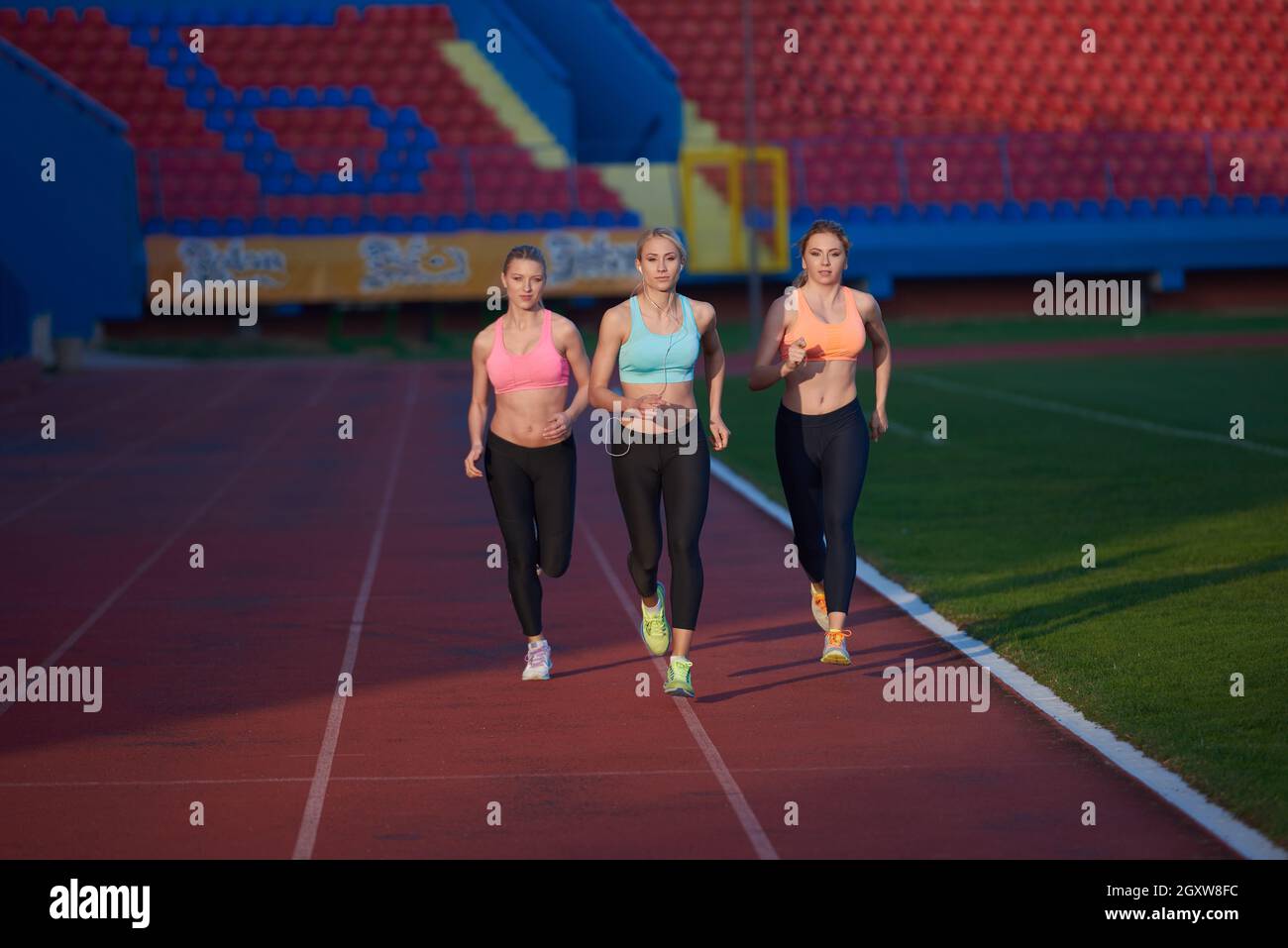 athlete woman group running on athletics race track on soccer stadium ...