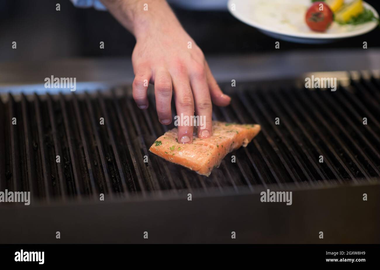 Master chef hands cooking grilled salmon fish with potatoes on a ...