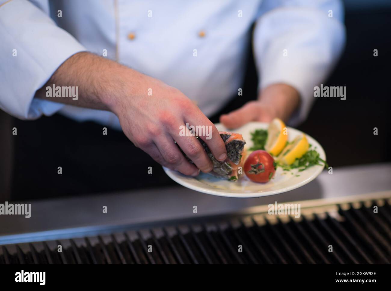 Master chef hands cooking grilled salmon fish with potatoes on a ...