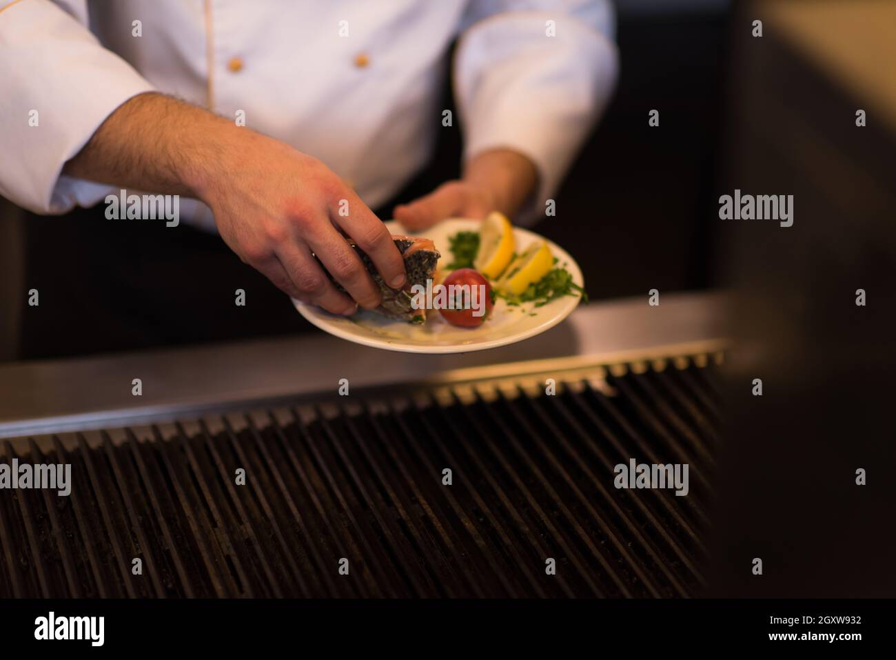 Master chef hands cooking grilled salmon fish with potatoes on a ...