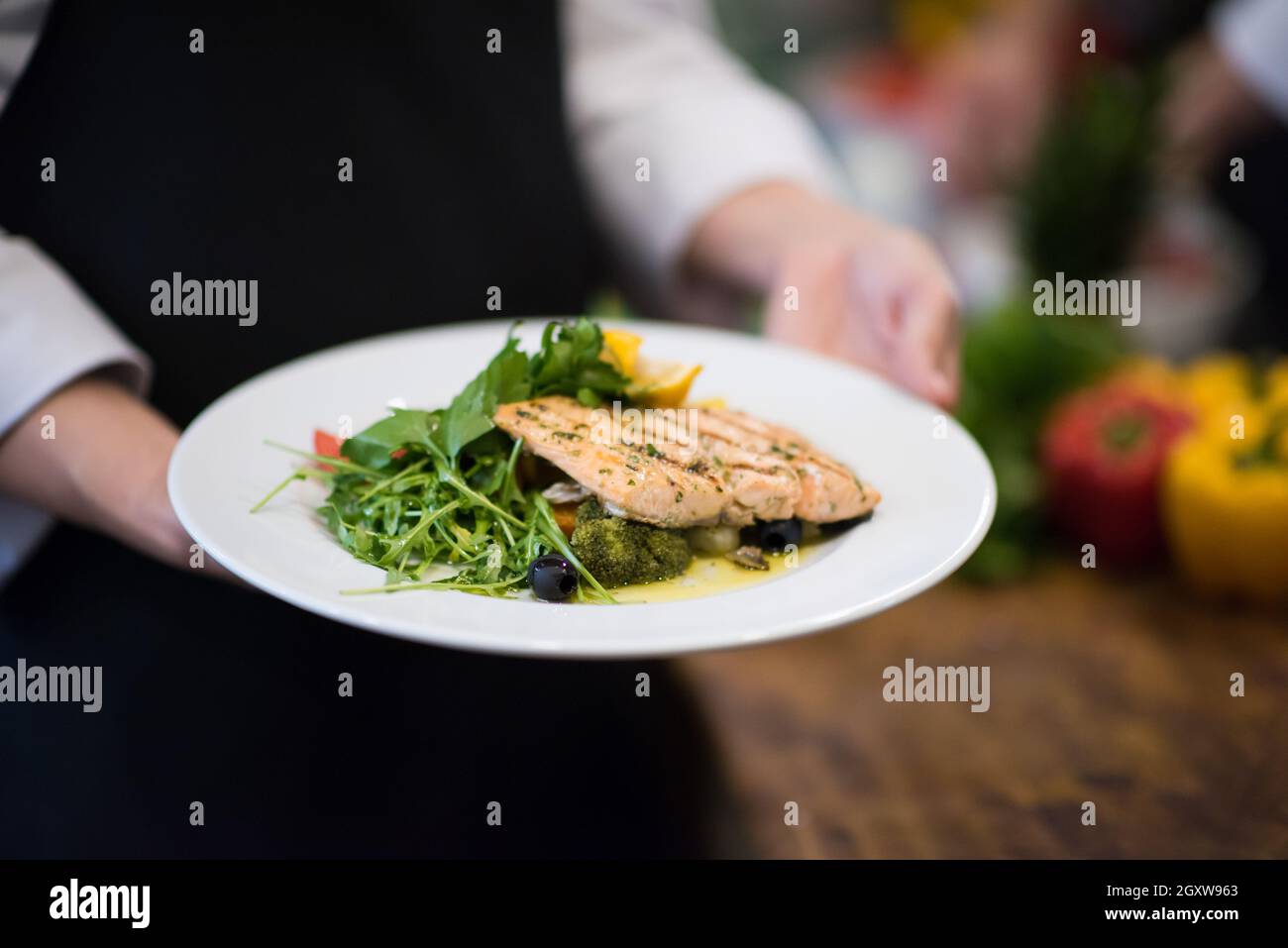 Chef hands holding fried Salmon fish fillet with vegetables for dinner ...