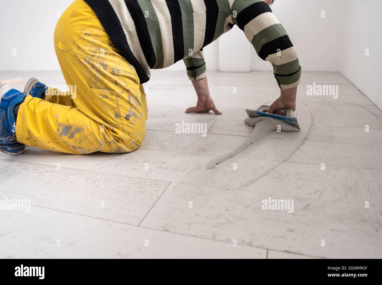 Grouting ceramic tiles. Tilers filling the space between ceramic wood ...