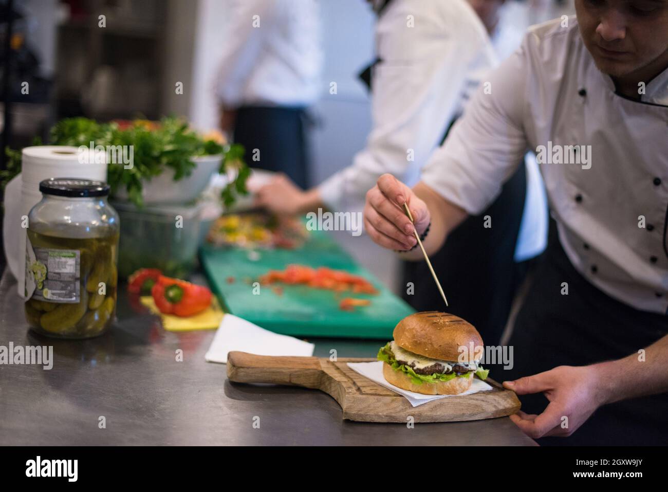 master chef putting toothpick on a burger in restaurant kitchen Stock ...