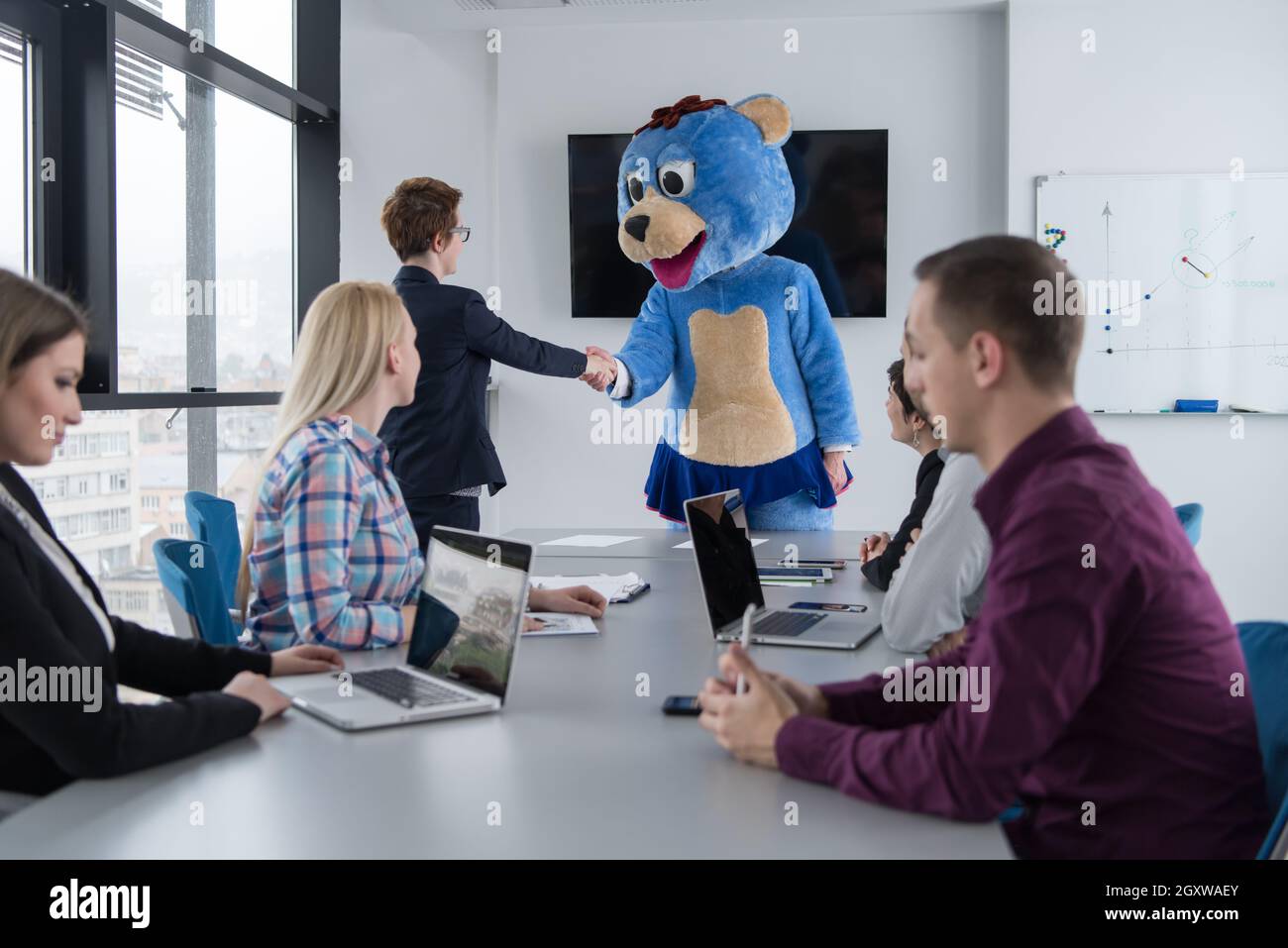 Boss dresed as teddy bear having fun with bussines people in modern ...