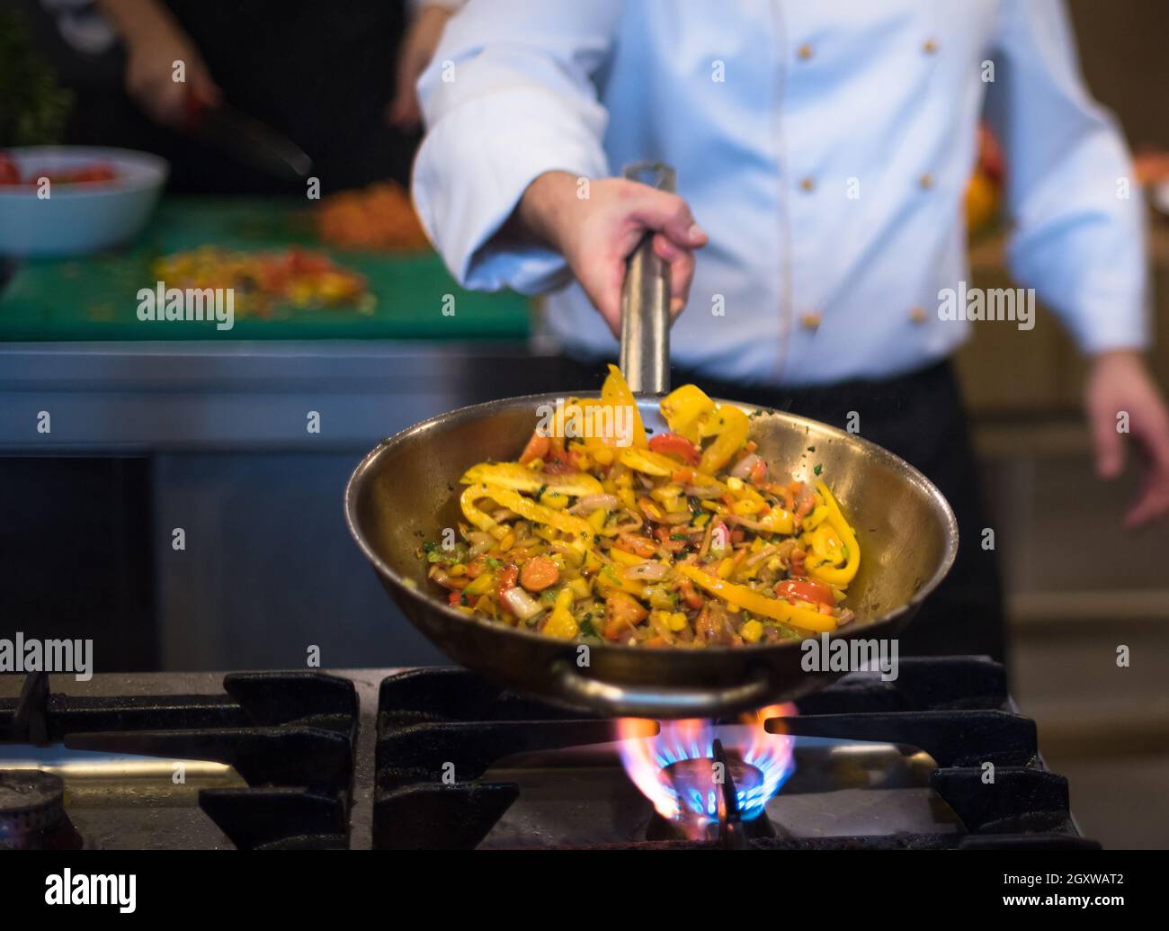Young male chef flipping vegetables in wok at commercial kitchen Stock ...