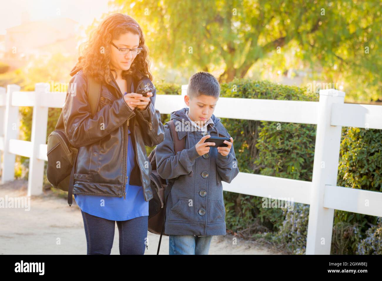 Hispanic Brother and Sister Wearing Backpacks Walking Texting On Cell ...