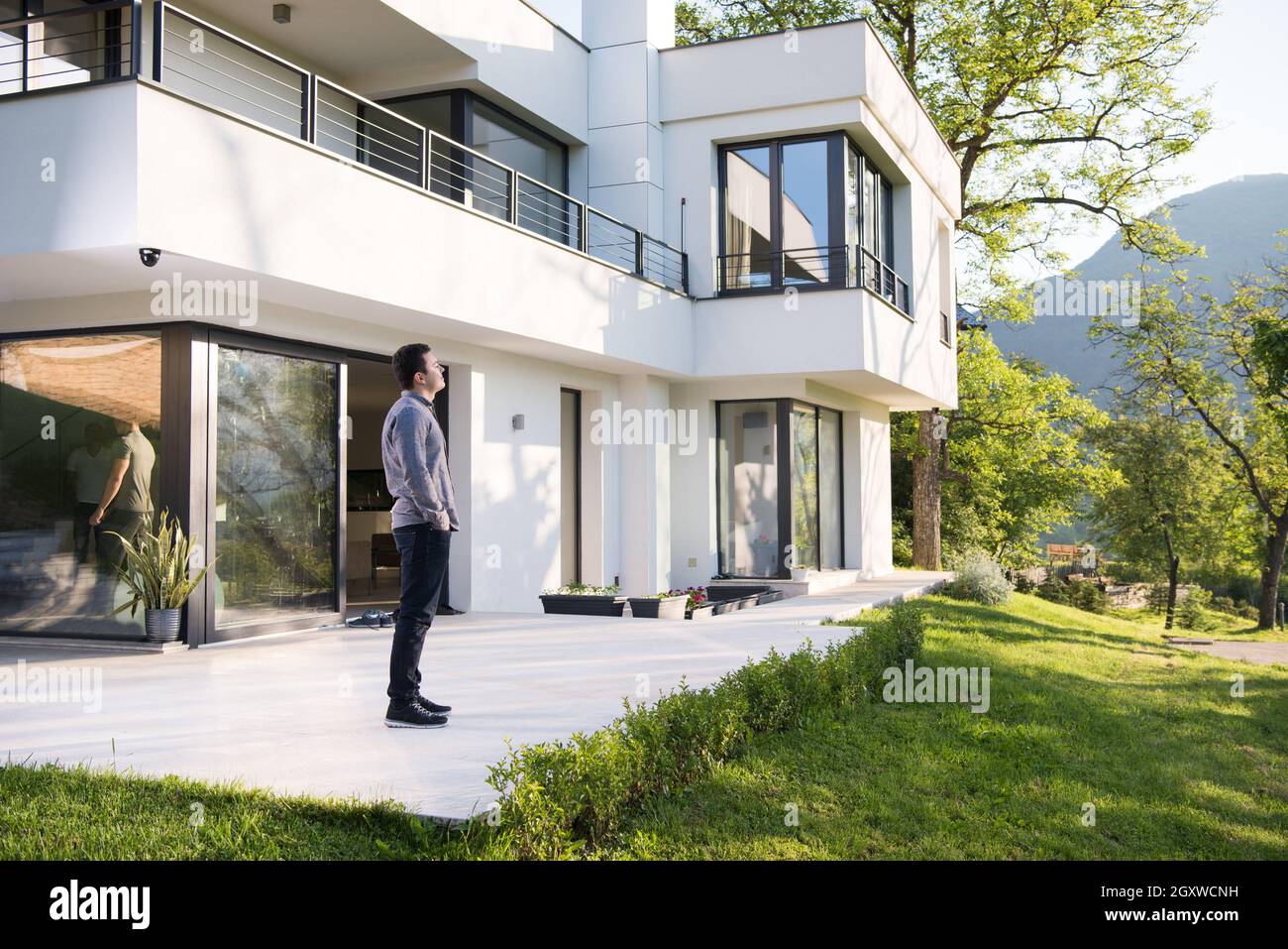 portrait of a young handsome successful man in front of his luxury home ...