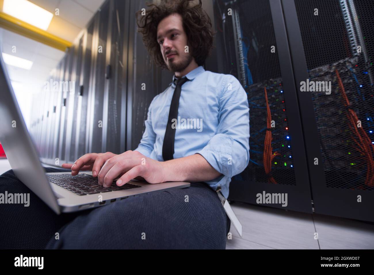 Male IT engineer working on a laptop in server room at modern data ...