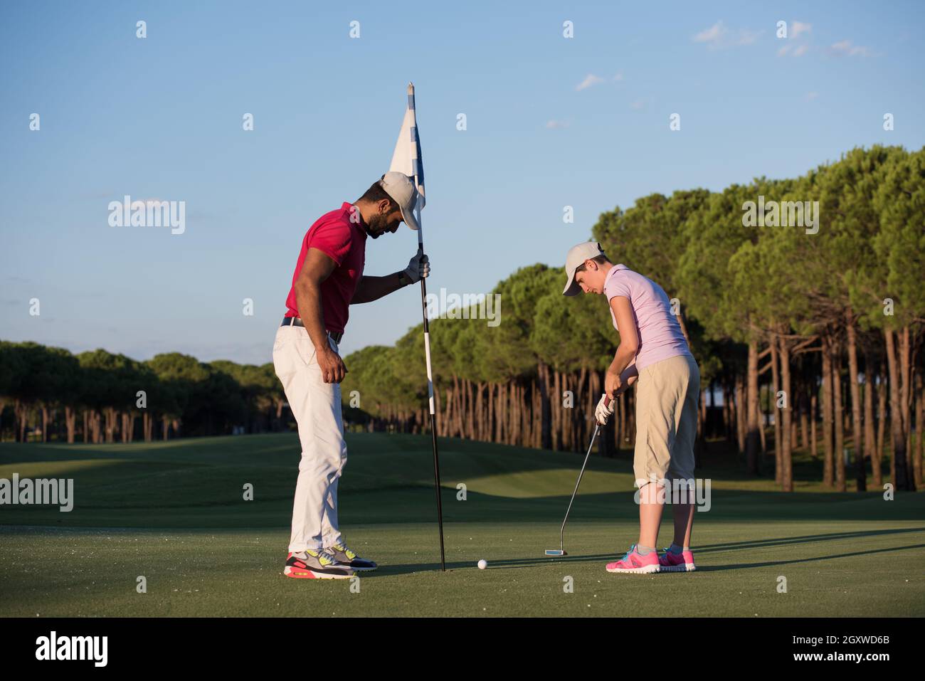 male golf instructor teaching female golf player, personal trainer ...