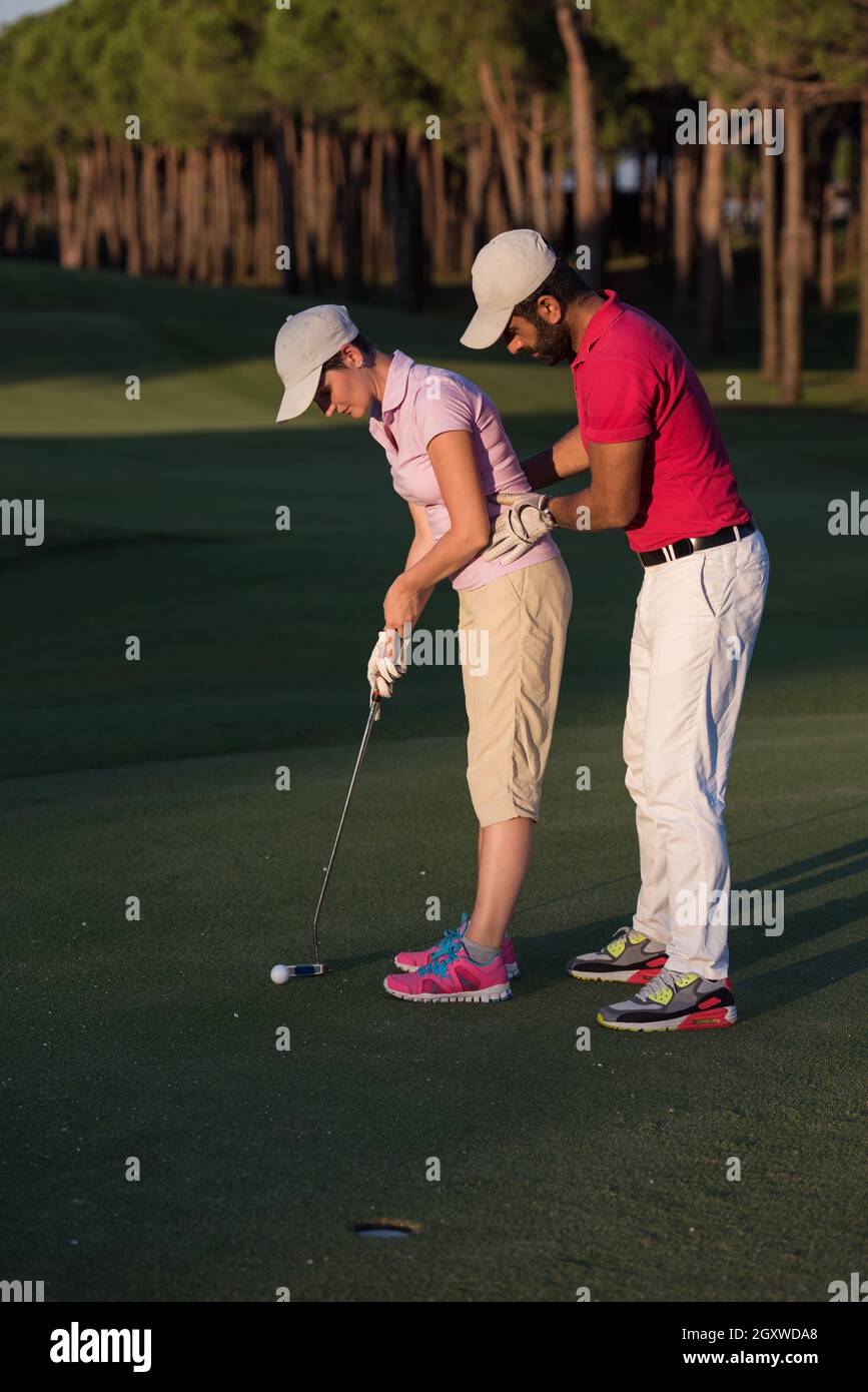male golf instructor teaching female golf player, personal trainer ...