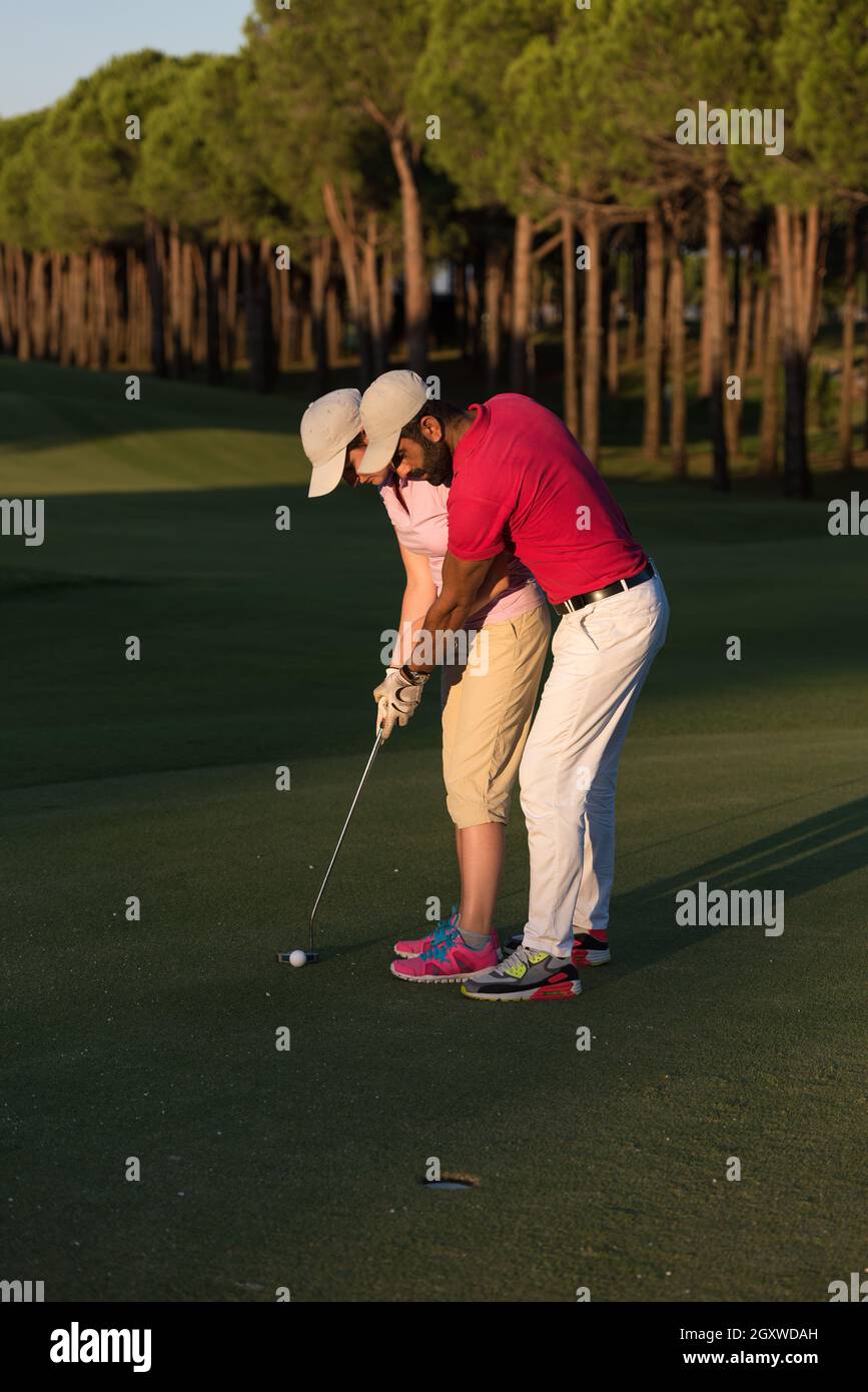 male golf instructor teaching female golf player, personal trainer ...
