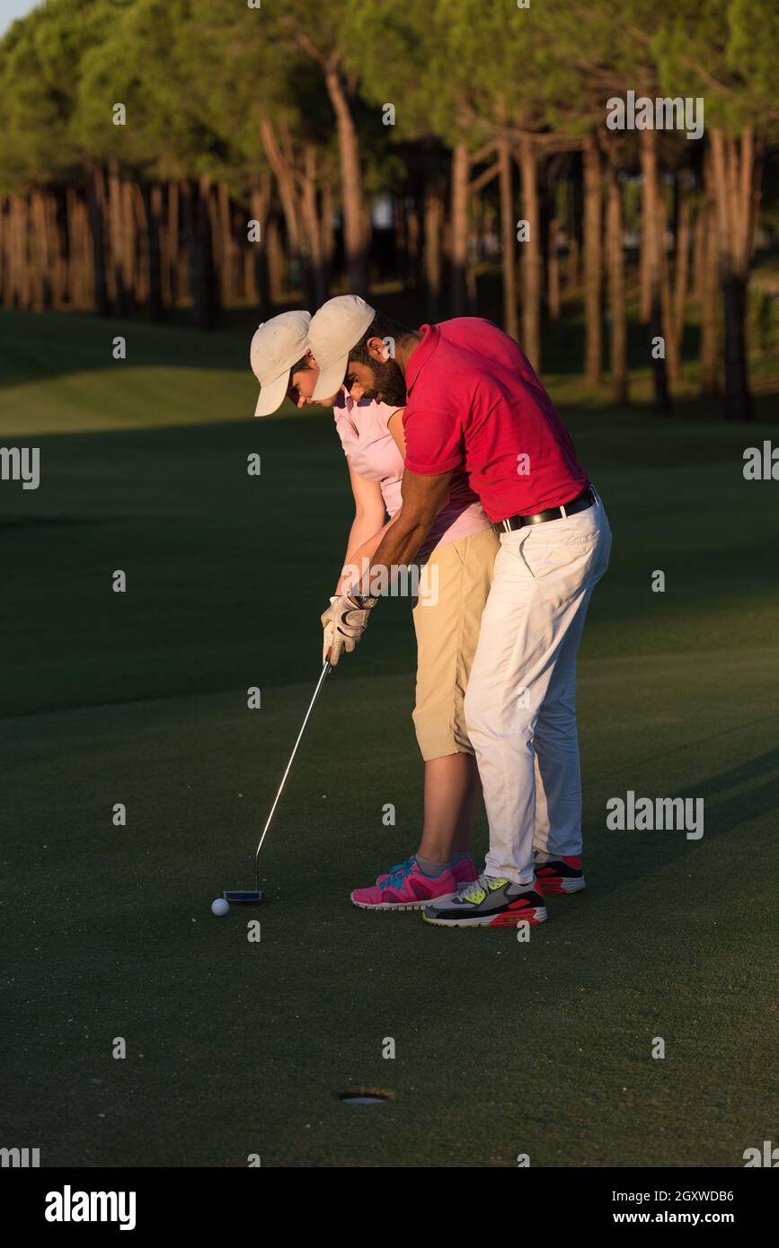 male golf instructor teaching female golf player, personal trainer ...
